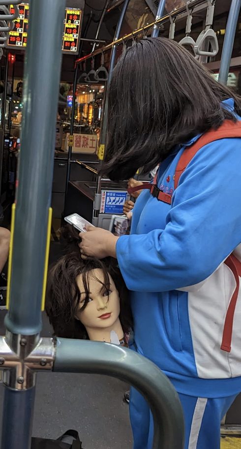 Female student calmly holds mannequin head while taking the bus ...